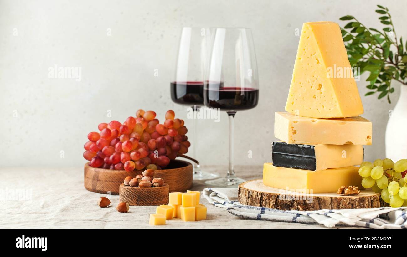 Banner of assorted cheeses with grapes and glasses of red wine on a ...