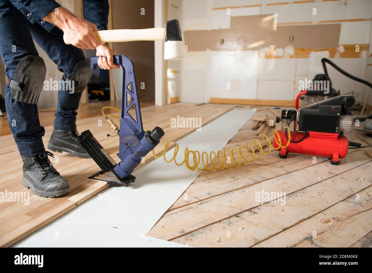 A Male Worker install wood floor on a house Stock Photo - Alamy