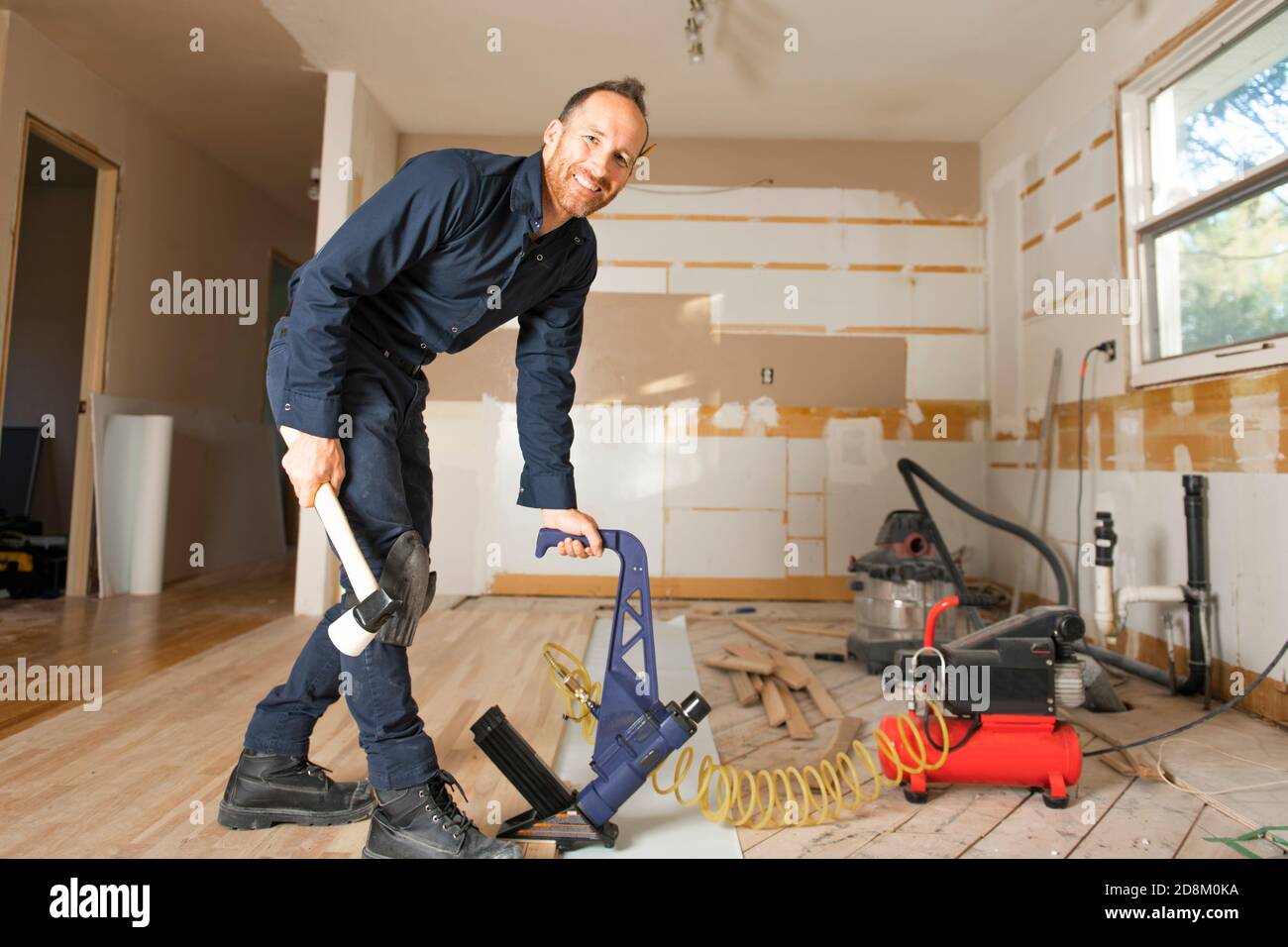 A Male Worker install wood floor on a house Stock Photo - Alamy