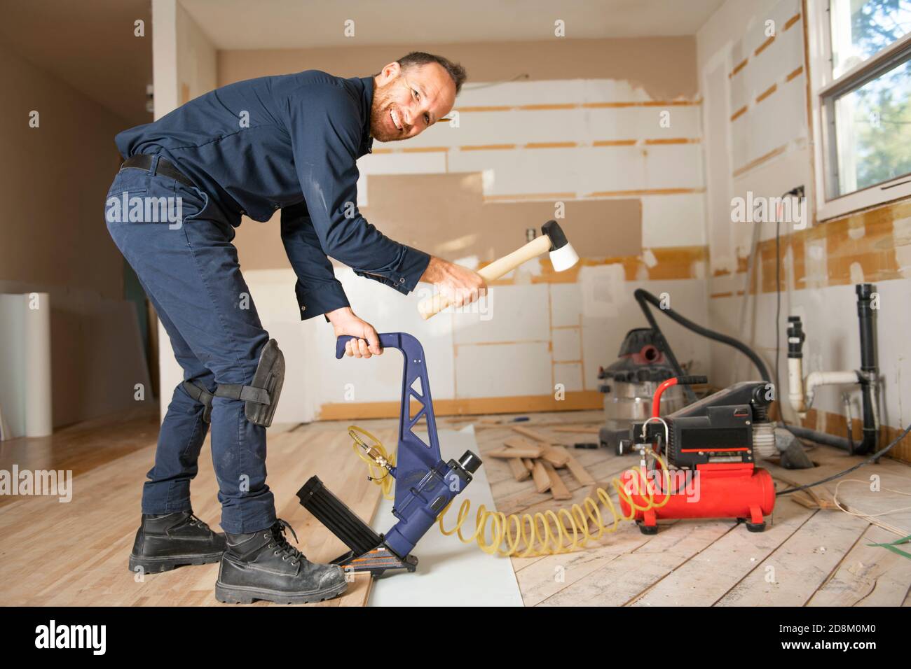A Male Worker install wood floor on a house Stock Photo - Alamy