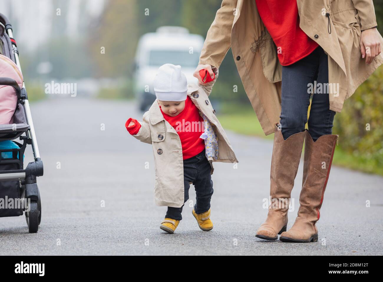 Cute funny happy baby making his first steps on a green lawn in autumn ...