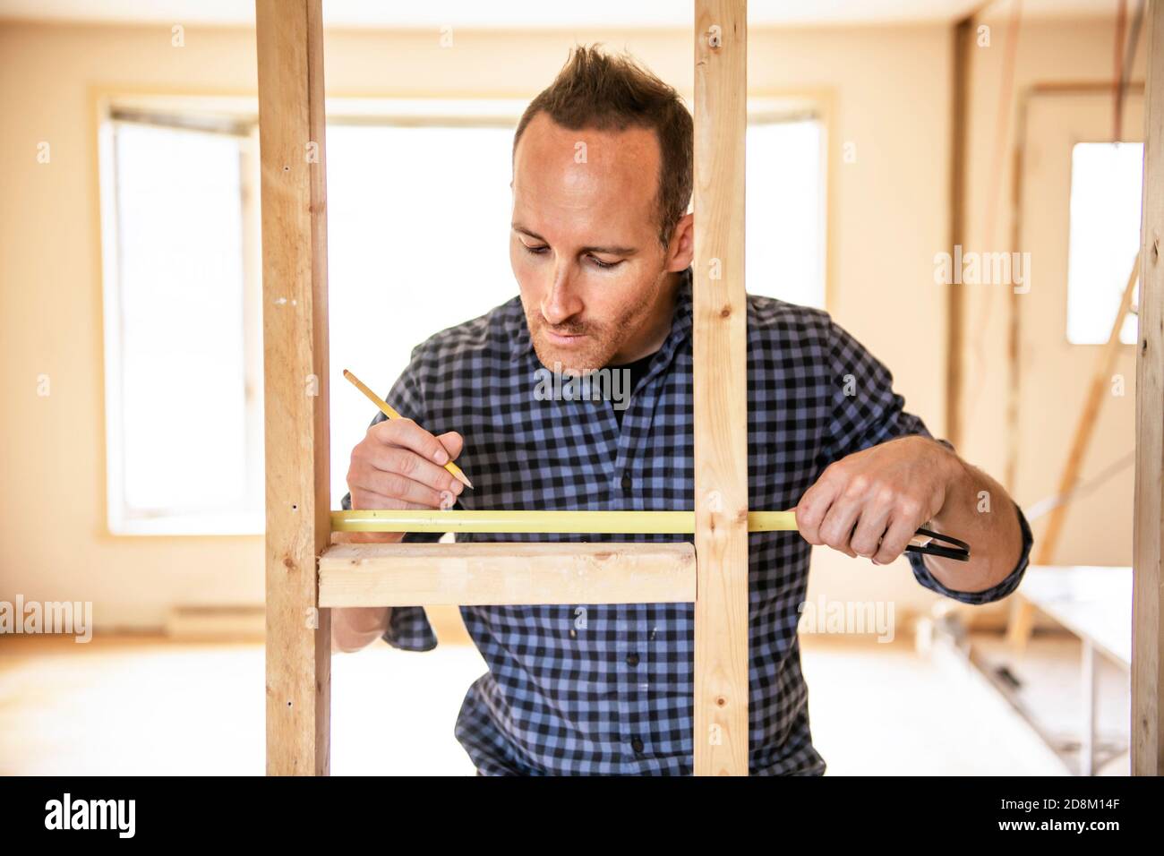 A man worker in the carpenter workroom renovation using tape Stock ...