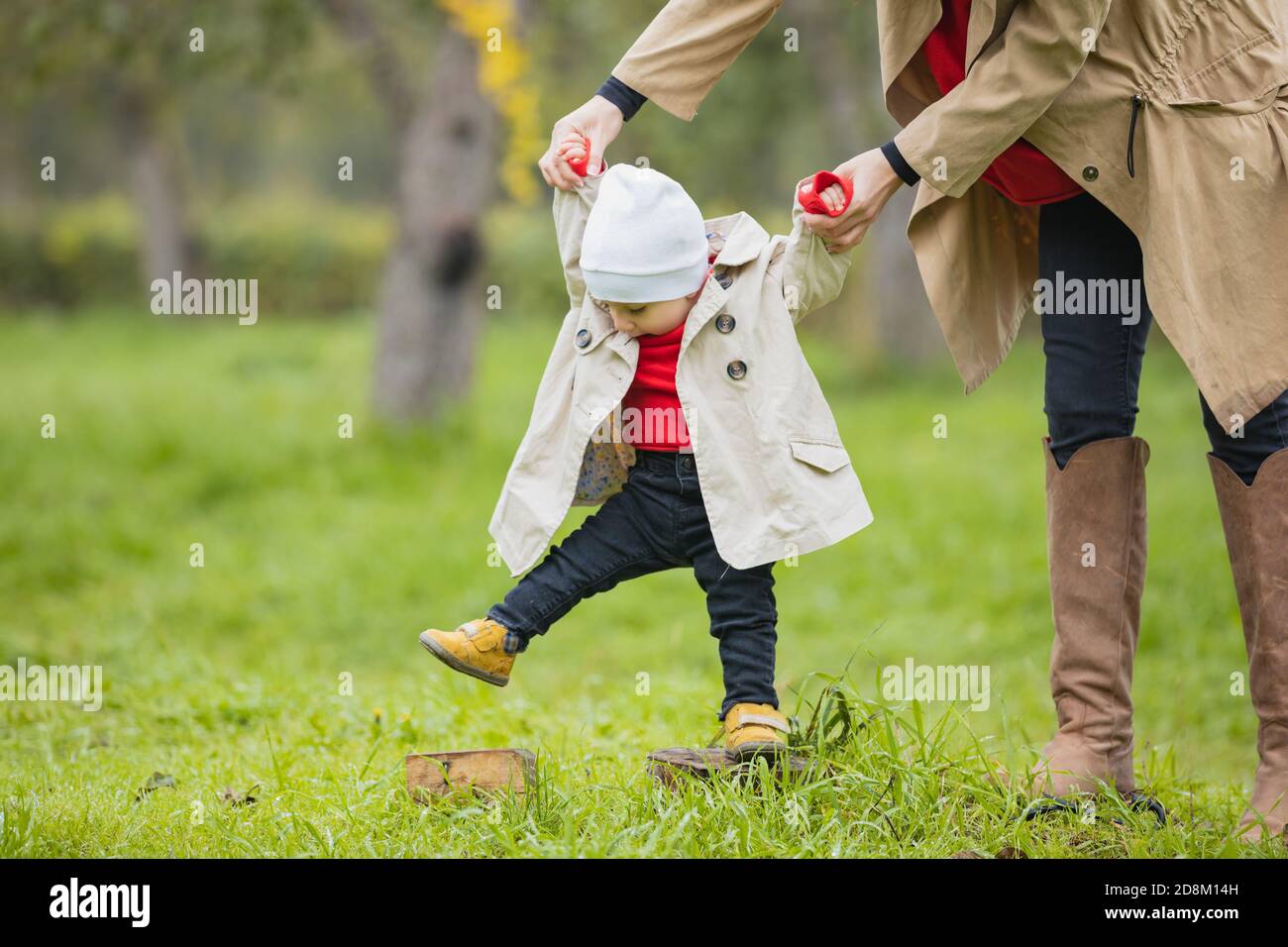 Cute funny happy baby making his first steps on a green lawn in autumn ...