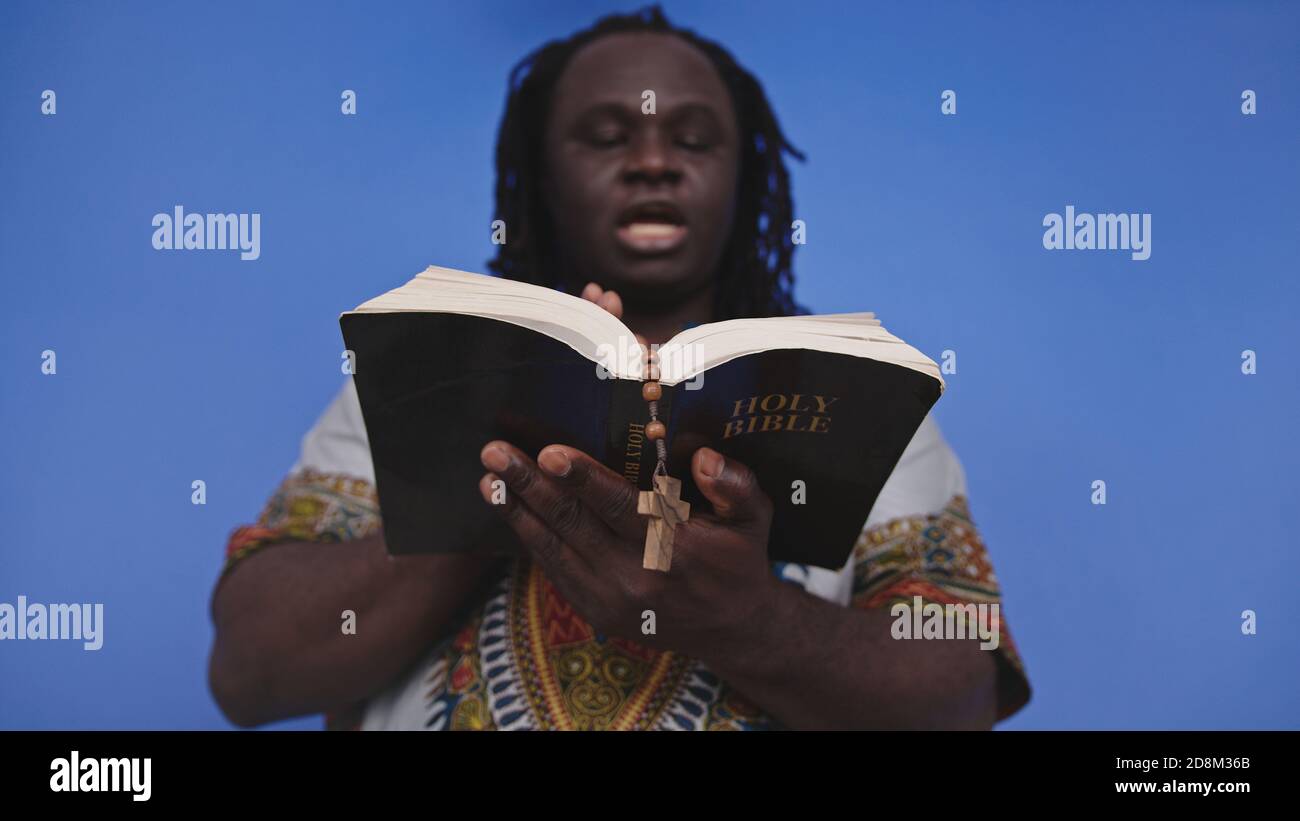 Portrait of african black man in traditional dress with rosary reading ...