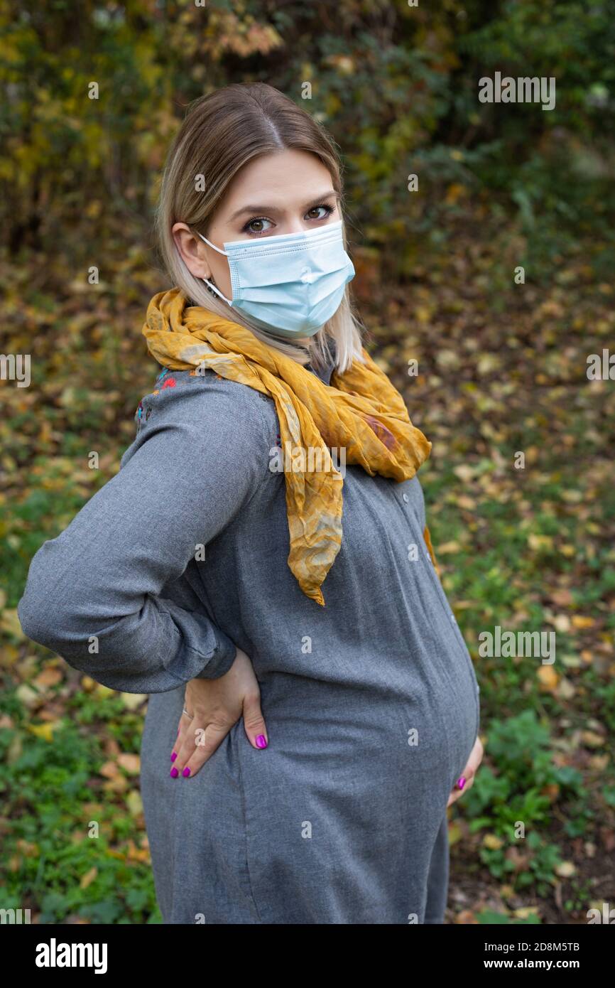 Beautiful pregnant woman in the park wearing surgical mask because of ...