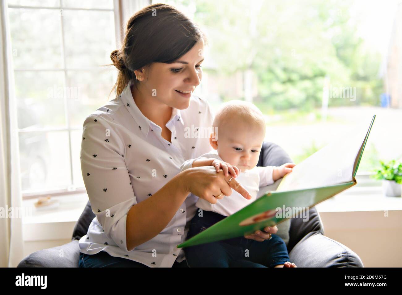happy loving family. pretty young mother reading a book to baby Stock ...