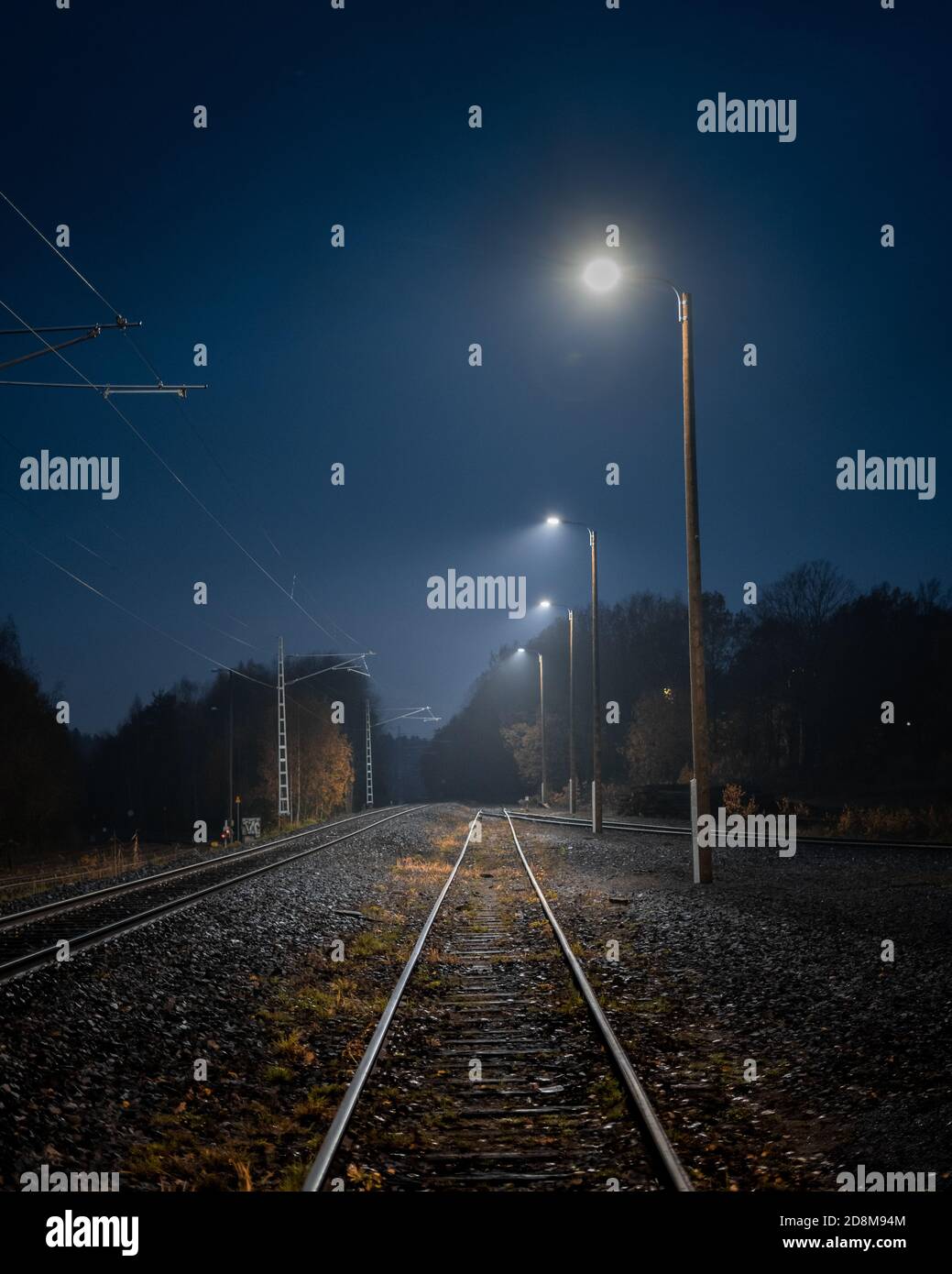 Atmospheric scene of a railroad track at night in autumn Stock Photo ...