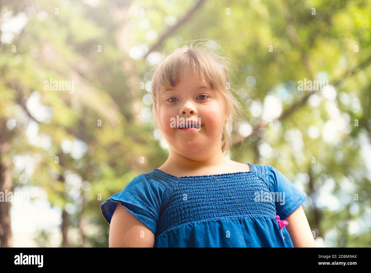 A portrait of trisomie 21 child girl outside having fun on a park Stock ...