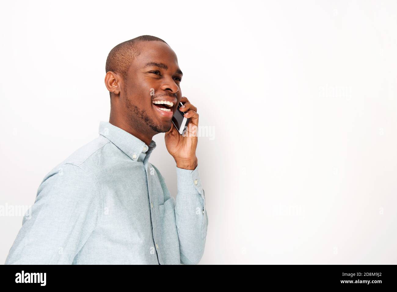 Side portrait of happy young black man talking with cellphone by white background Stock Photo ...