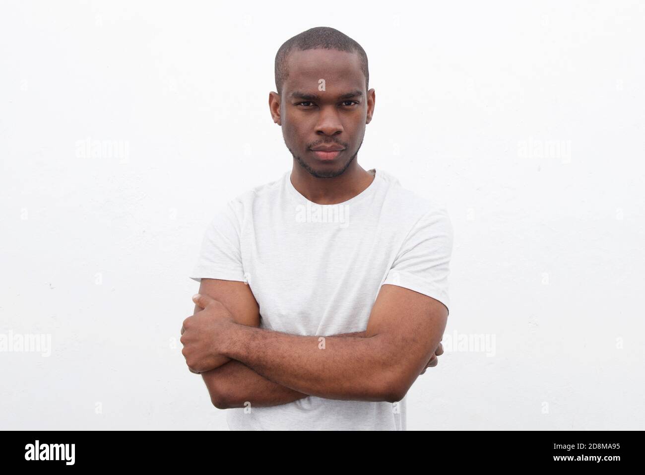 Portrait of handsome young black man posing with arms crossed against ...
