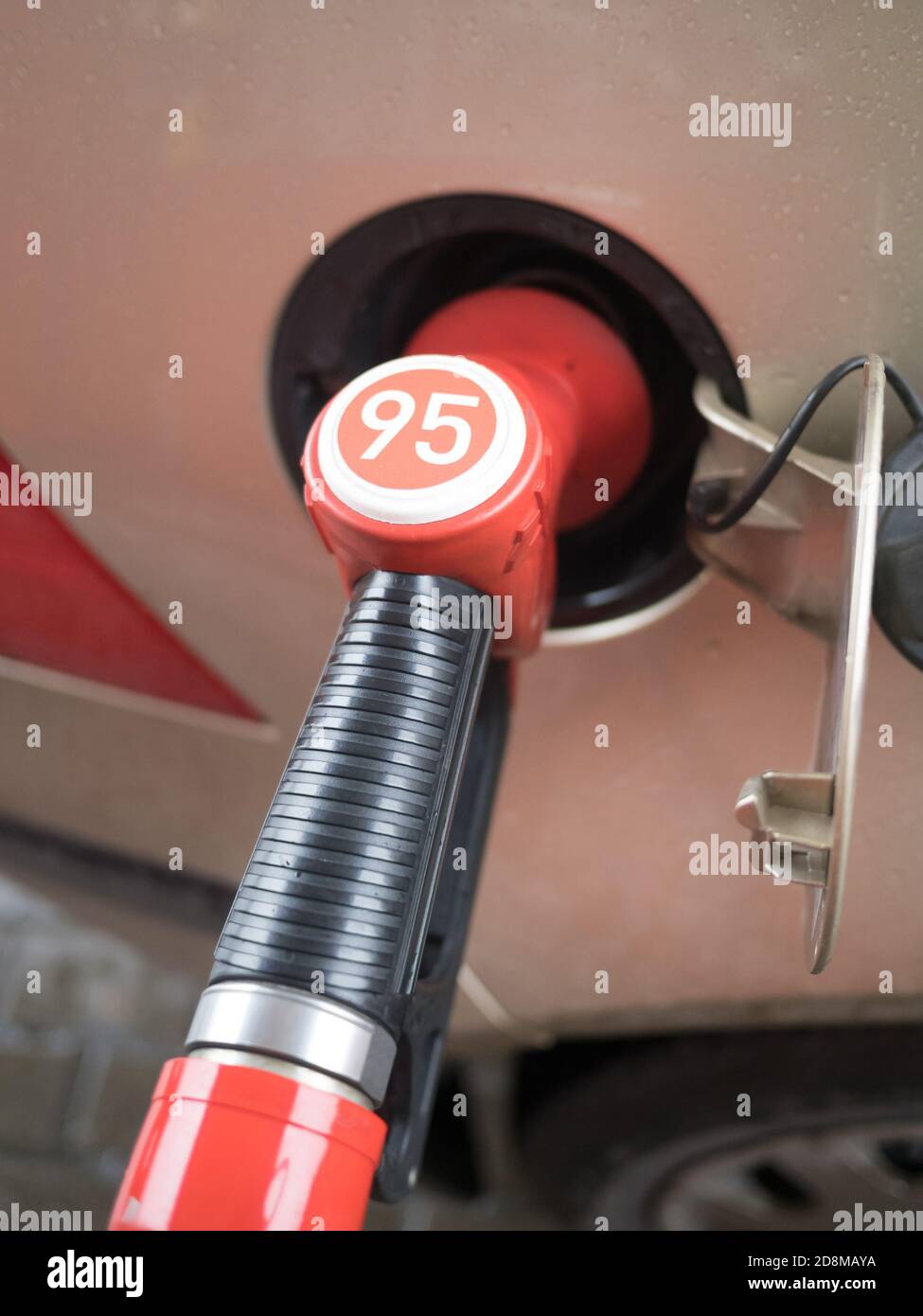 A 95 fuel delivery gun nozzle inserted into the car tank at a gas ...