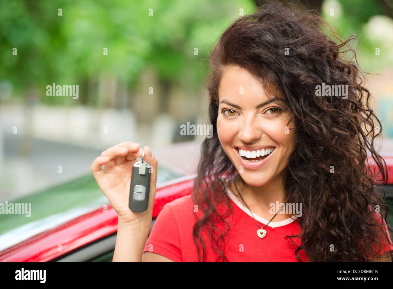 Woman showing her new car key smiling happy posing in the parking lot ...