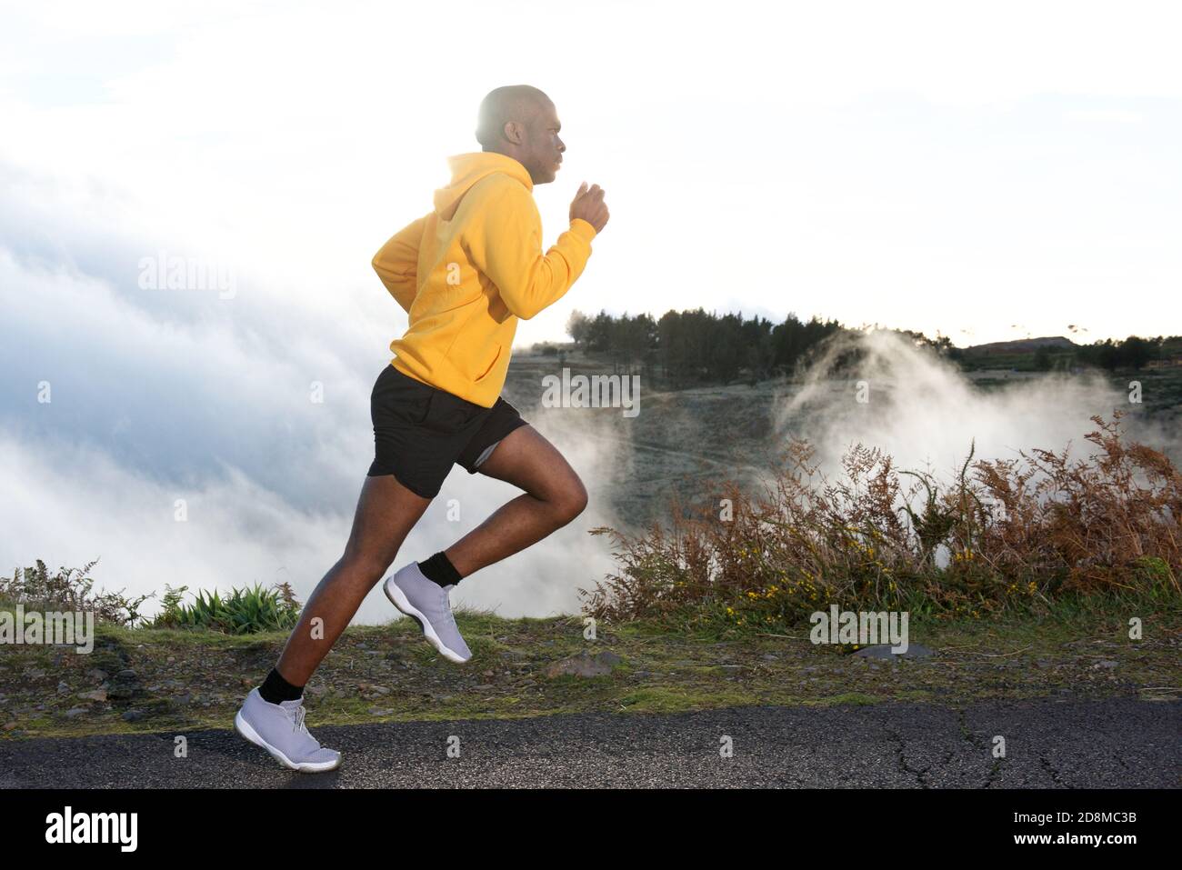 Full body side portrait of young black man road running in nature Stock ...