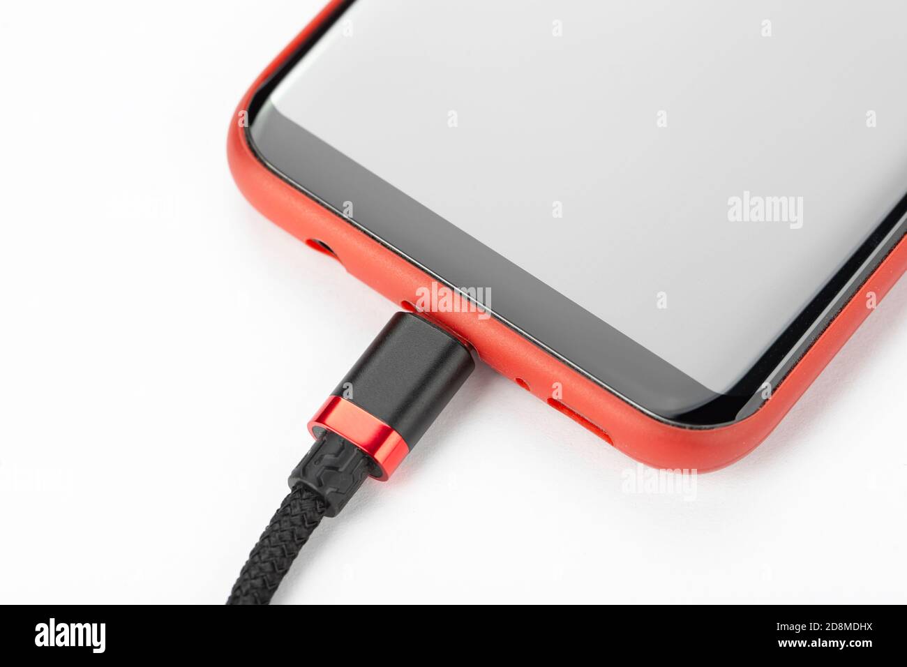 Mobile phone in a red case with a connected cable for charging power on ...