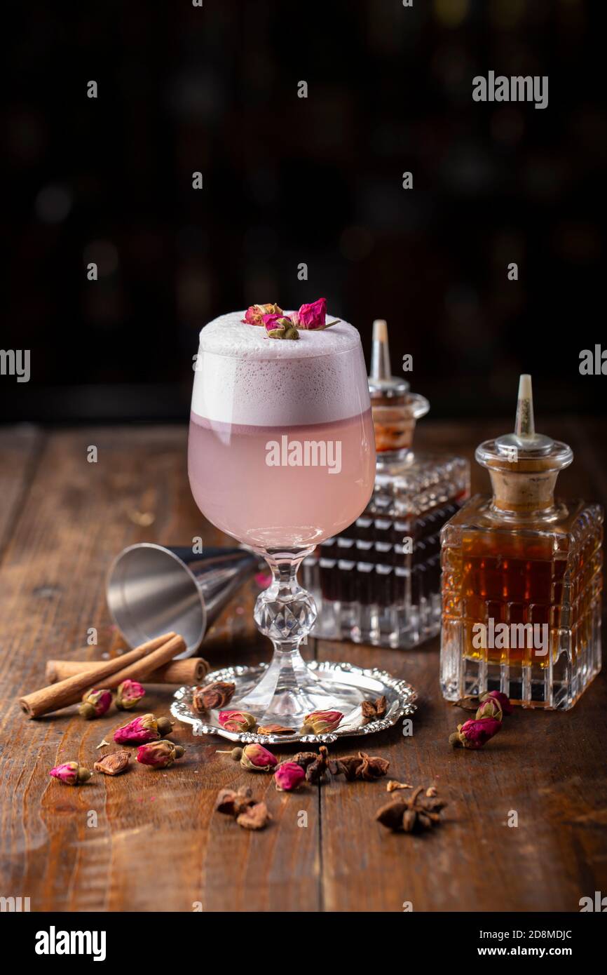Pink alcoholic cocktail with foam, decorated with dry roses. drink on ...