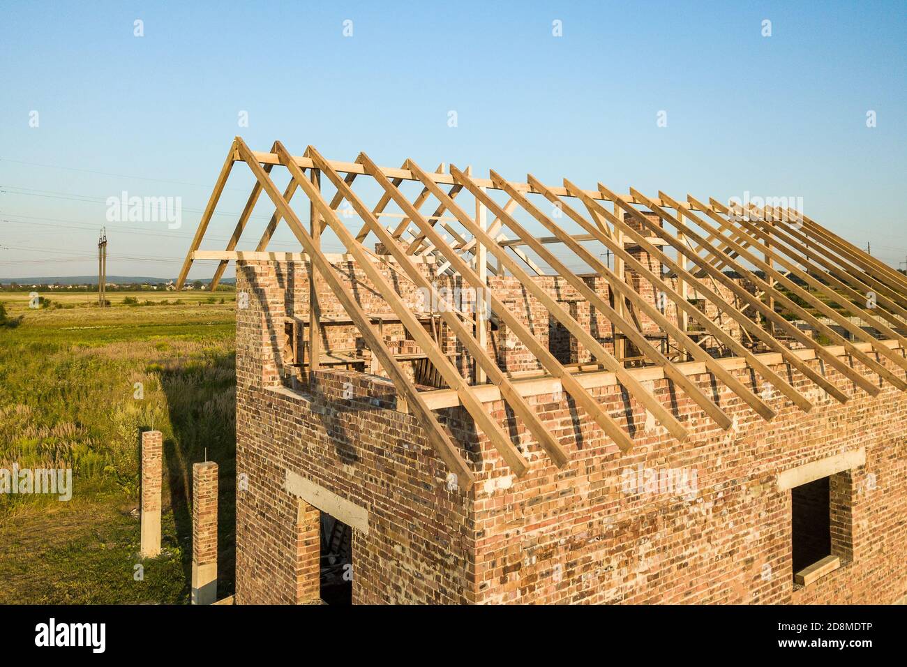 Unfinished brick house with wooden roof structure under construction ...