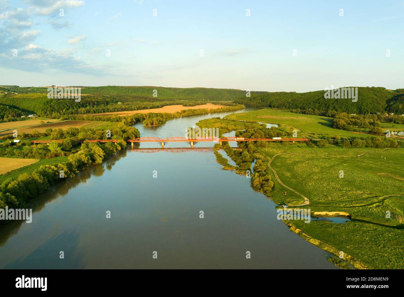 Aerial view of a narrow road bridge stretching over muddy wide river in ...
