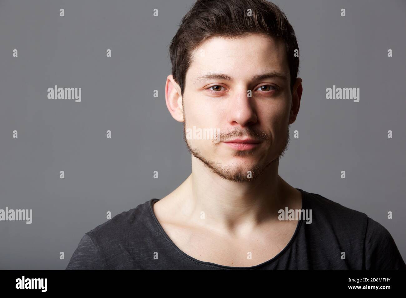 Close up horizontal portrait of handsome young man against gray ...