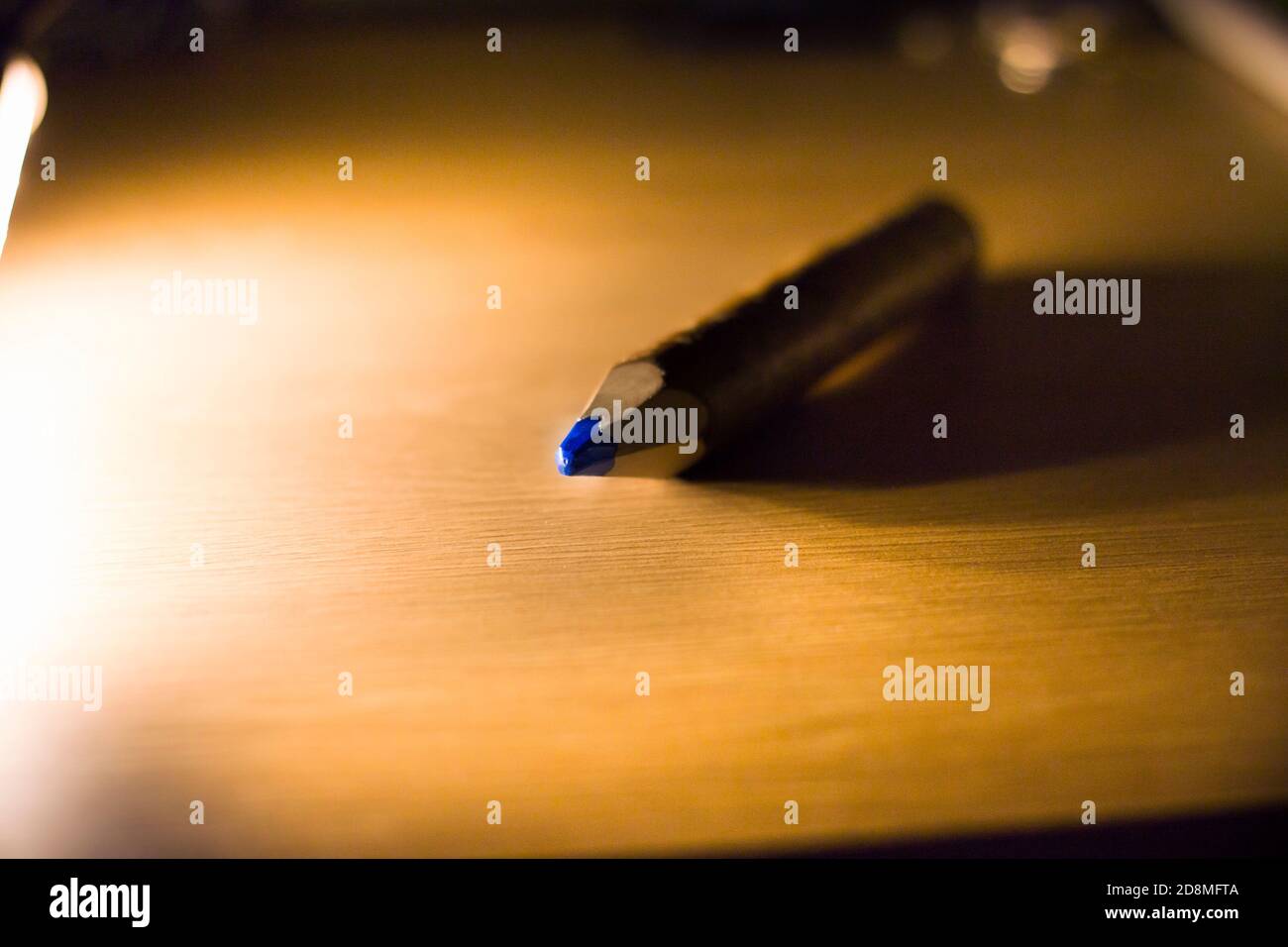 Top view of blue sharp pencil lying on wooden yellow table or desk ...