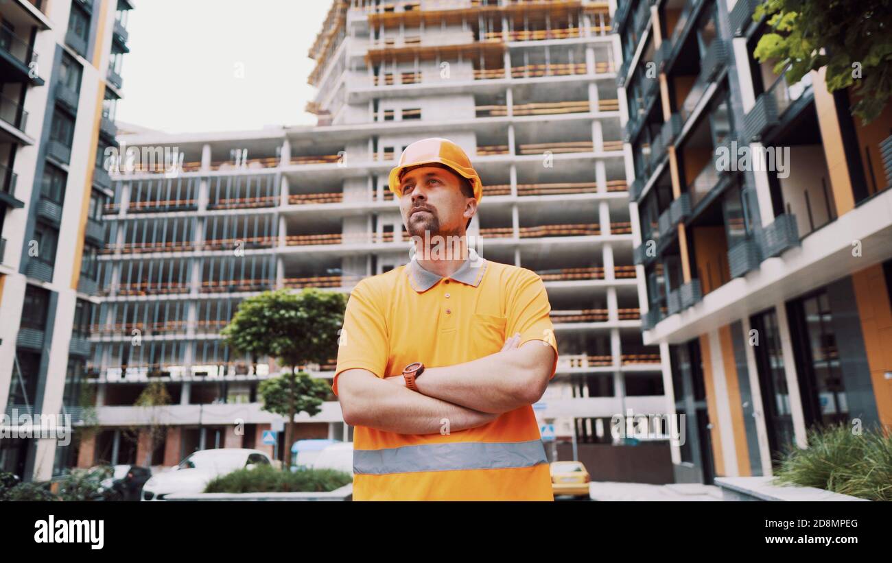 Young caucasian constructor with arms crossed in safety helmet and ...