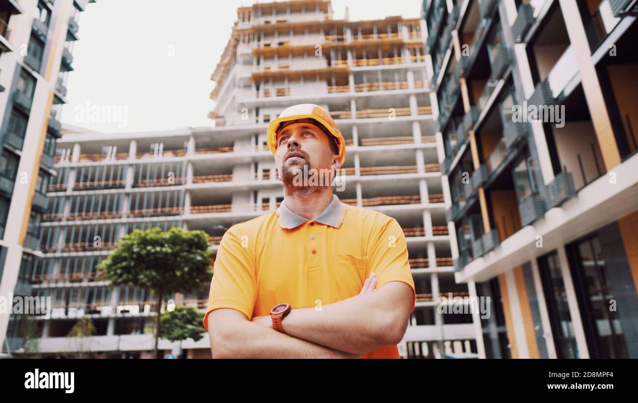 Young caucasian constructor with arms crossed in safety helmet and ...