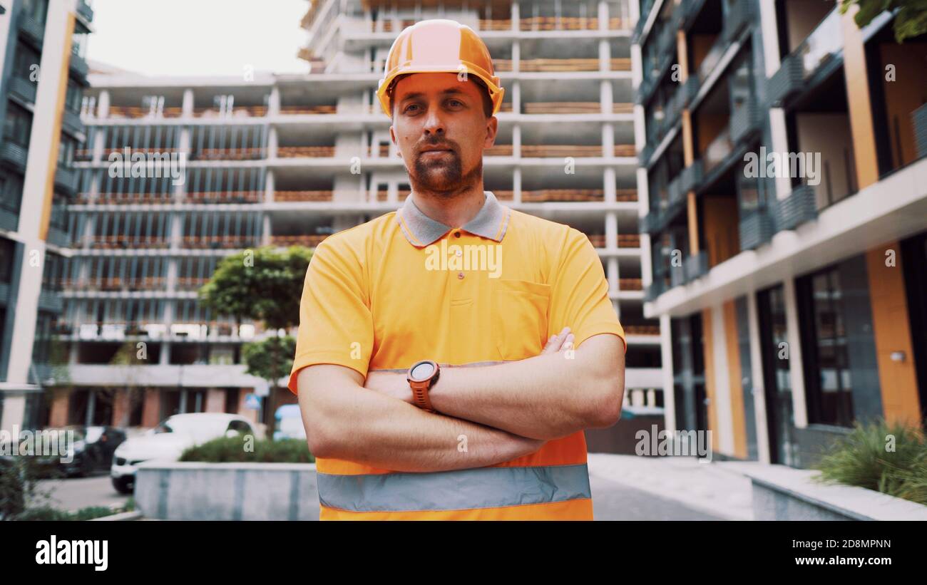 Young caucasian constructor with arms crossed in safety helmet and ...