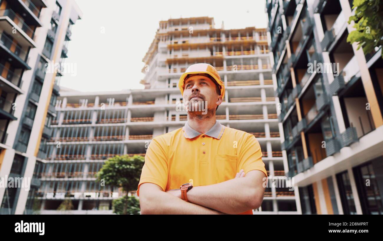 Young caucasian constructor with arms crossed in safety helmet and ...