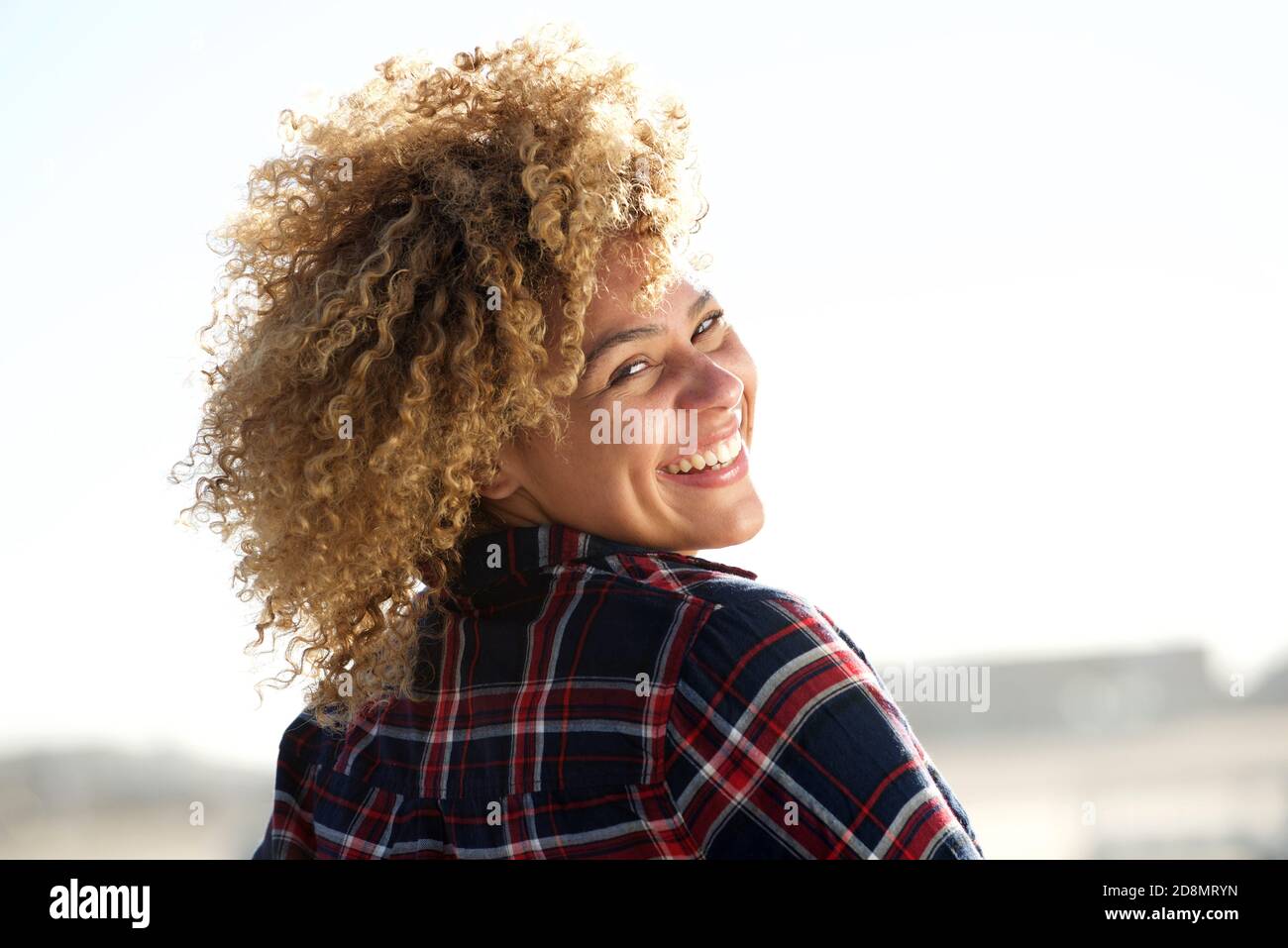 Portrait from behind of happy young woman with curly hair turning ...