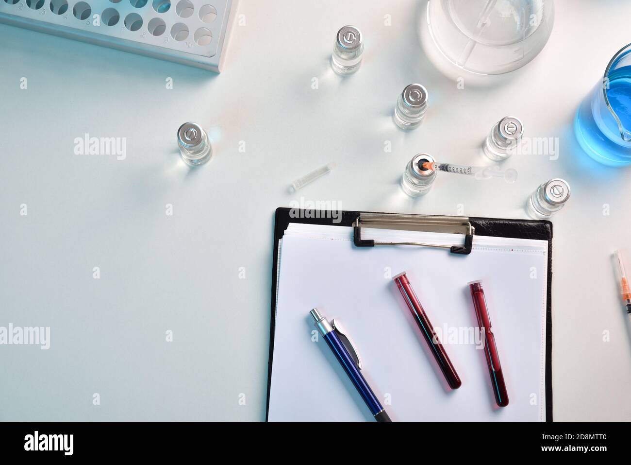 Notepad and pen on a lab table full of vials and supplies. Horizontal ...