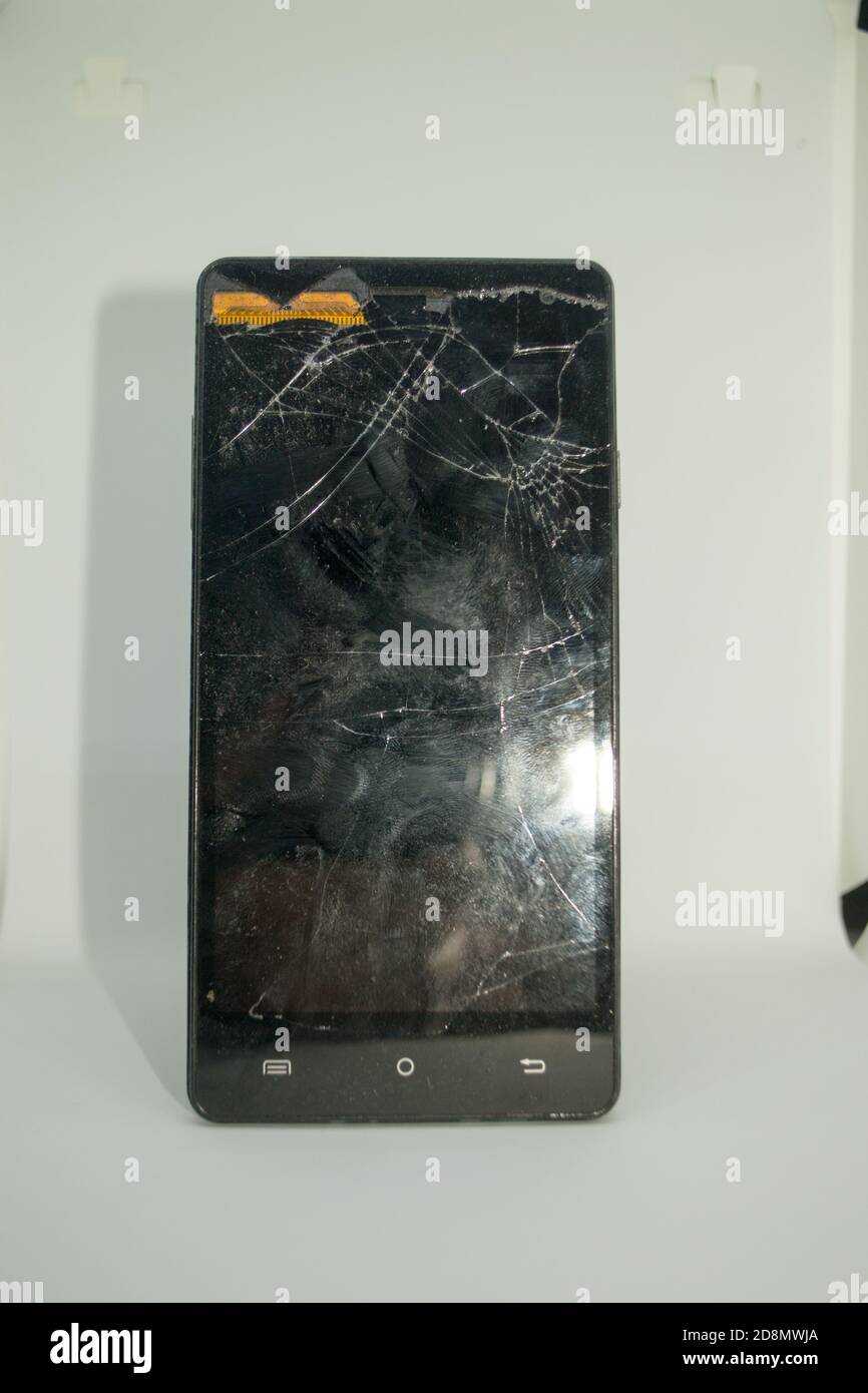 A color black mobile smartphone with a crashed/cracked or broken screen ...