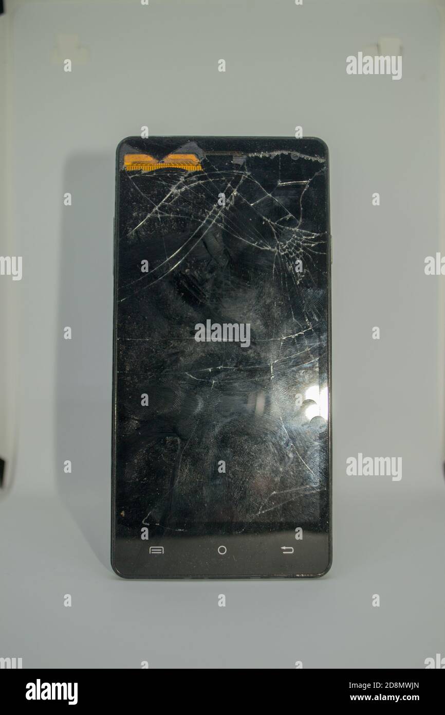 A color black mobile smartphone with a crashed/cracked or broken screen ...