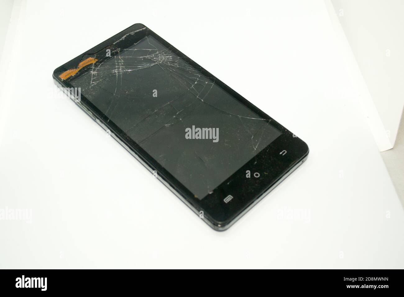 A color black mobile smartphone with a crashed/cracked or broken screen ...