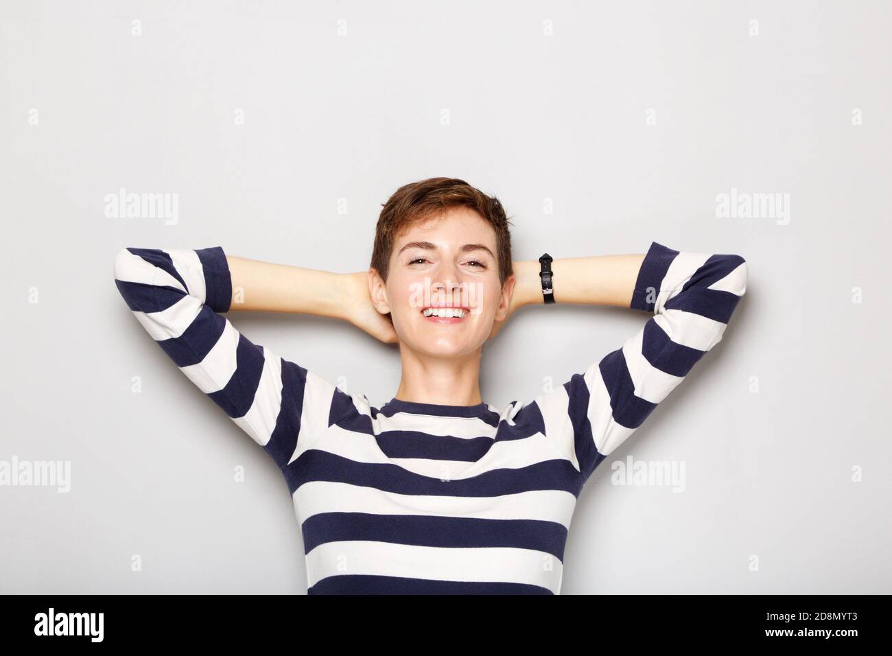 Portrait of cool young woman smiling with hands behind head Stock Photo ...
