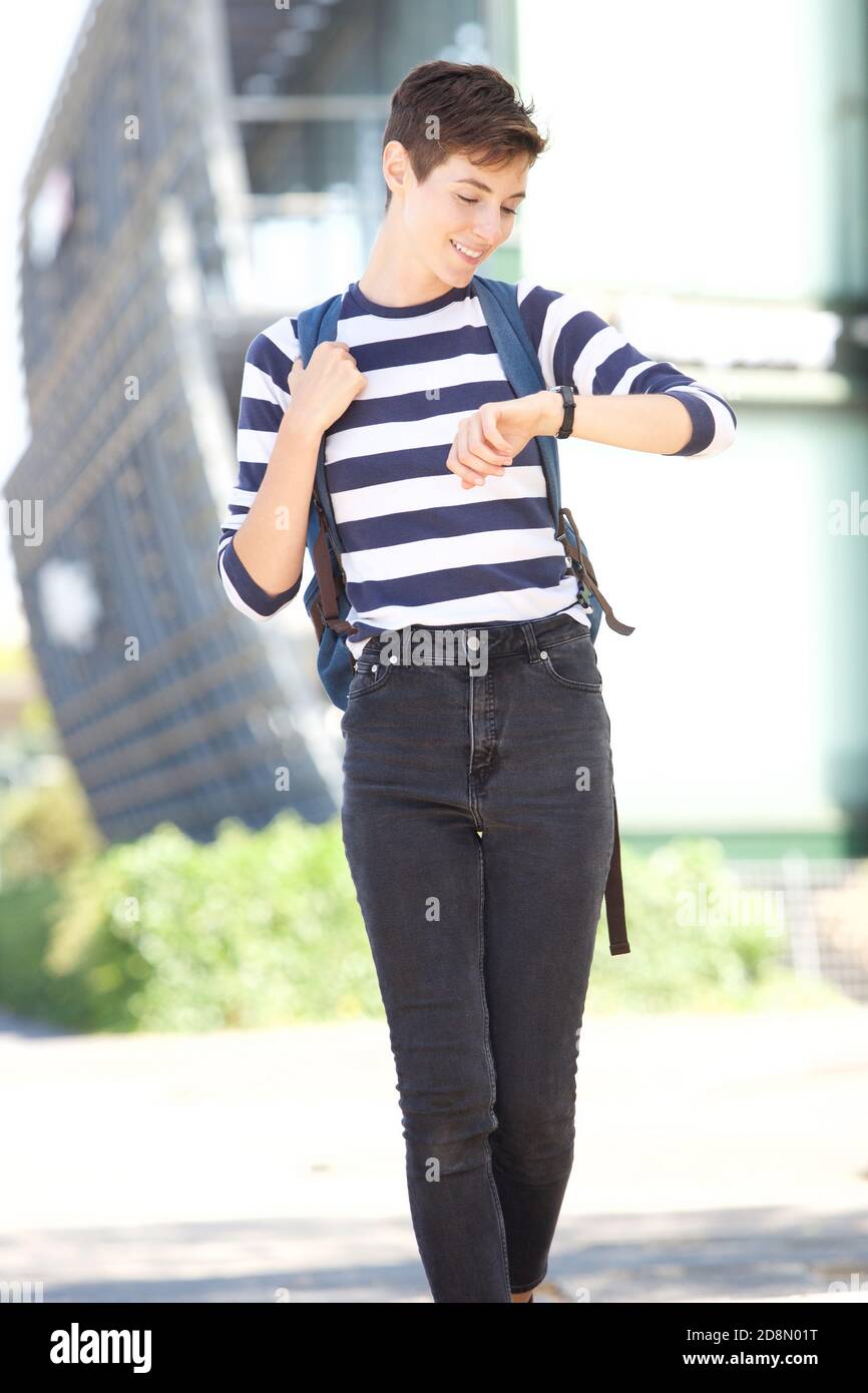 Portrait of smiling college student walking and looking at watch Stock ...