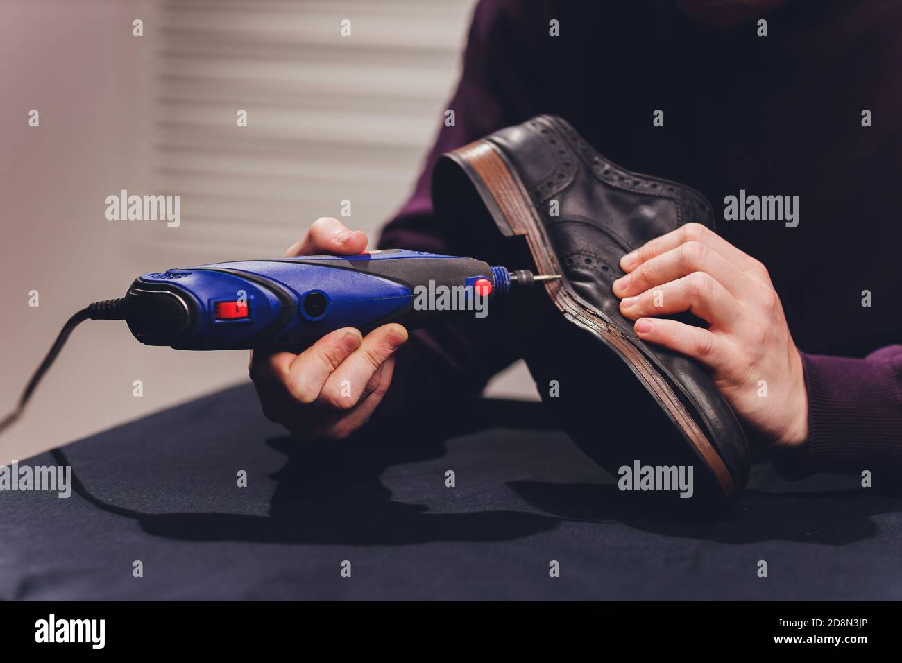 A shoemaker cuts the sole of a Shoe with a shoemaker's automatic cutter ...