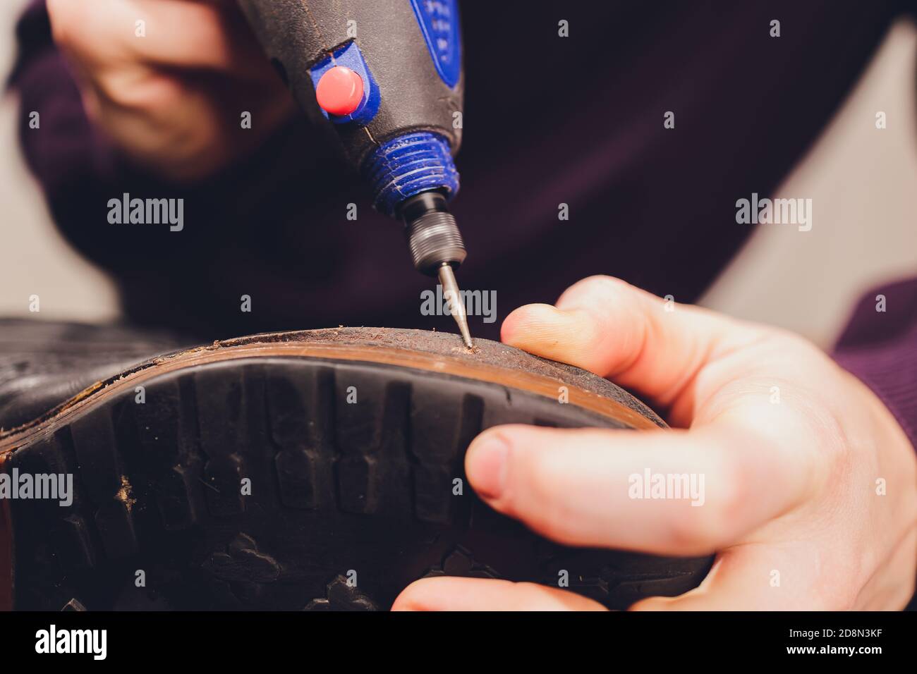 A shoemaker cuts the sole of a Shoe with a shoemaker's automatic cutter ...