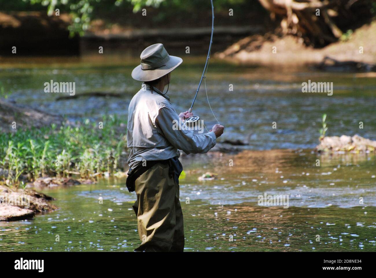 Person, man, wading into the river under a bridge to fly fish Stock ...