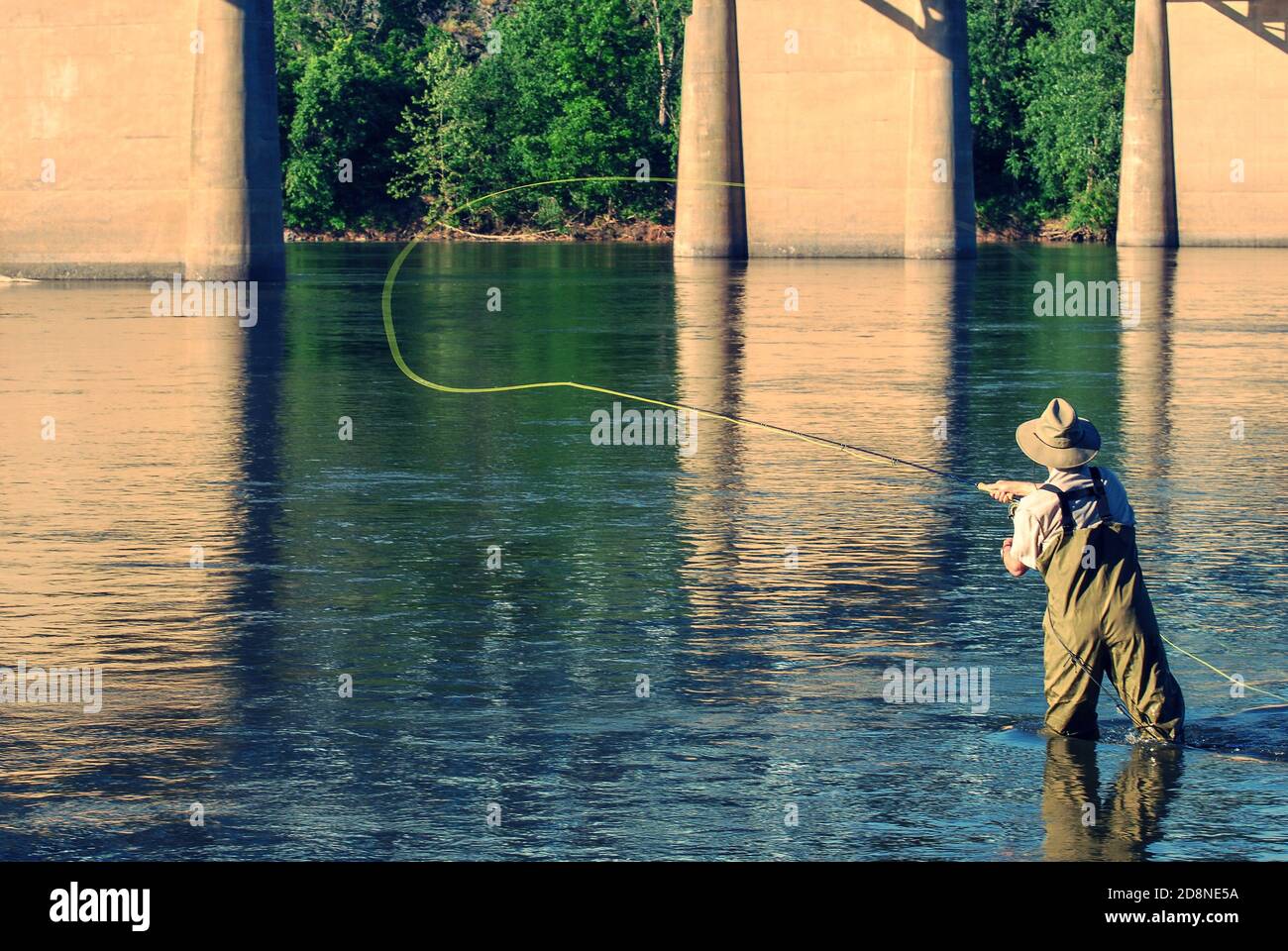 Person, man, wading into the river under a bridge to fly fish Stock ...