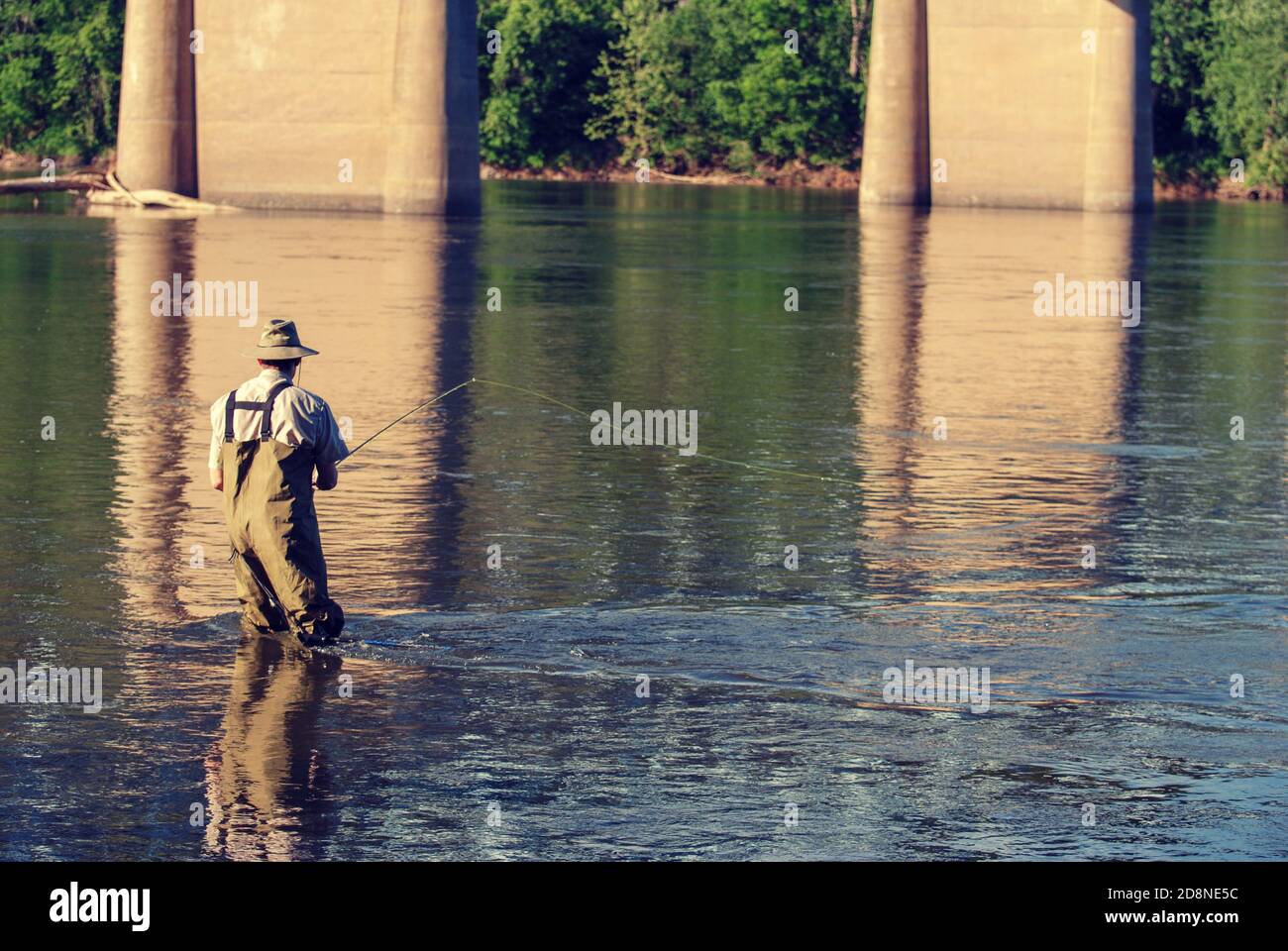 Person, man, wading into the river under a bridge to fly fish Stock ...