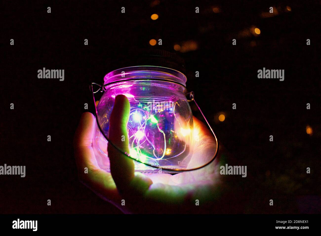 Hand holding mason Jar filled with neon LED lights inside Stock Photo ...