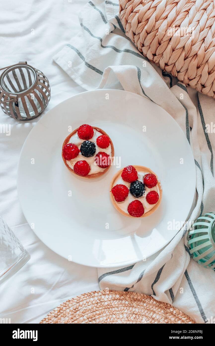 Delicious raspberry tartlets with cream filling on white plate. Fresh ...