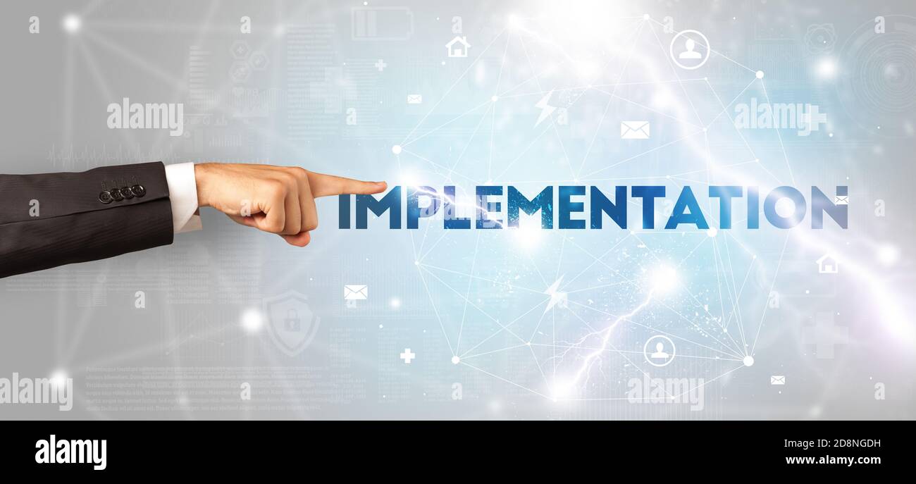 Hand pointing at IMPLEMENTATION inscription, modern technology concept ...