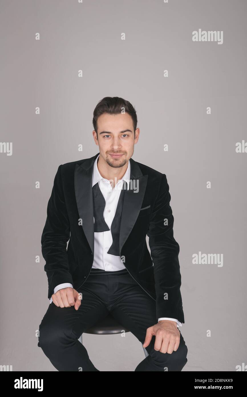 Studio portrait of a young caucasian man in a tuxedo, collar unbuttoned ...