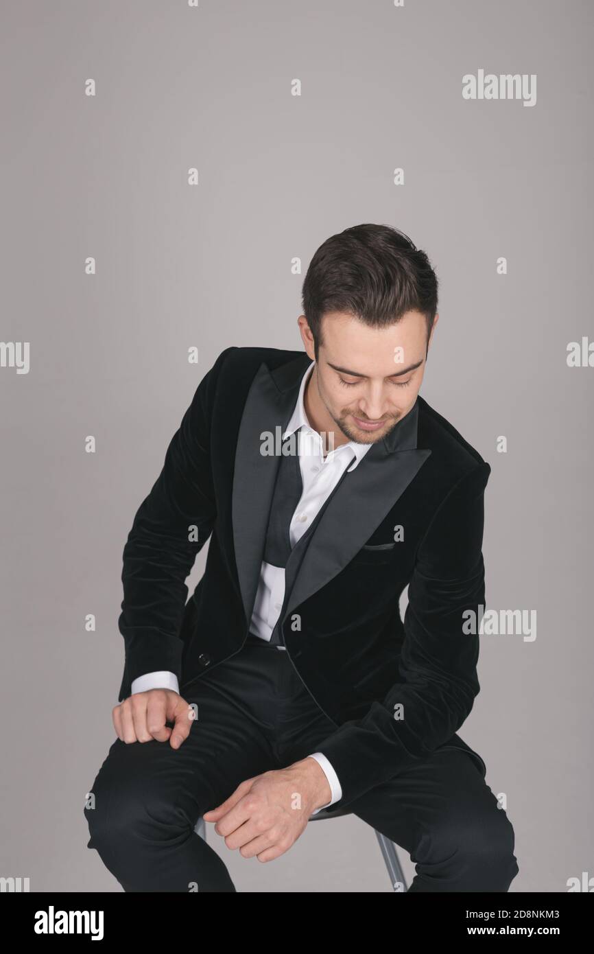 Studio portrait of a young caucasian man in a tuxedo, collar unbuttoned ...
