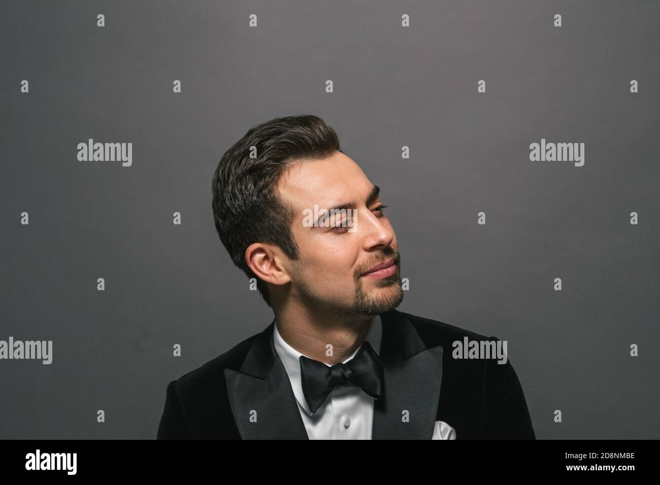 Studio portrait of a young caucasian man in a tuxedo, collar unbuttoned ...