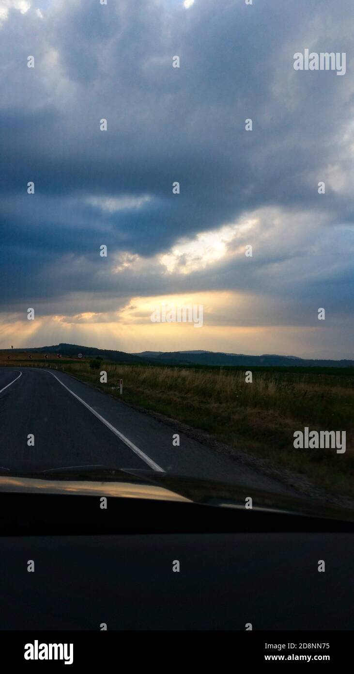Vertical shot of a road through the countryside and the cloudy sunset ...
