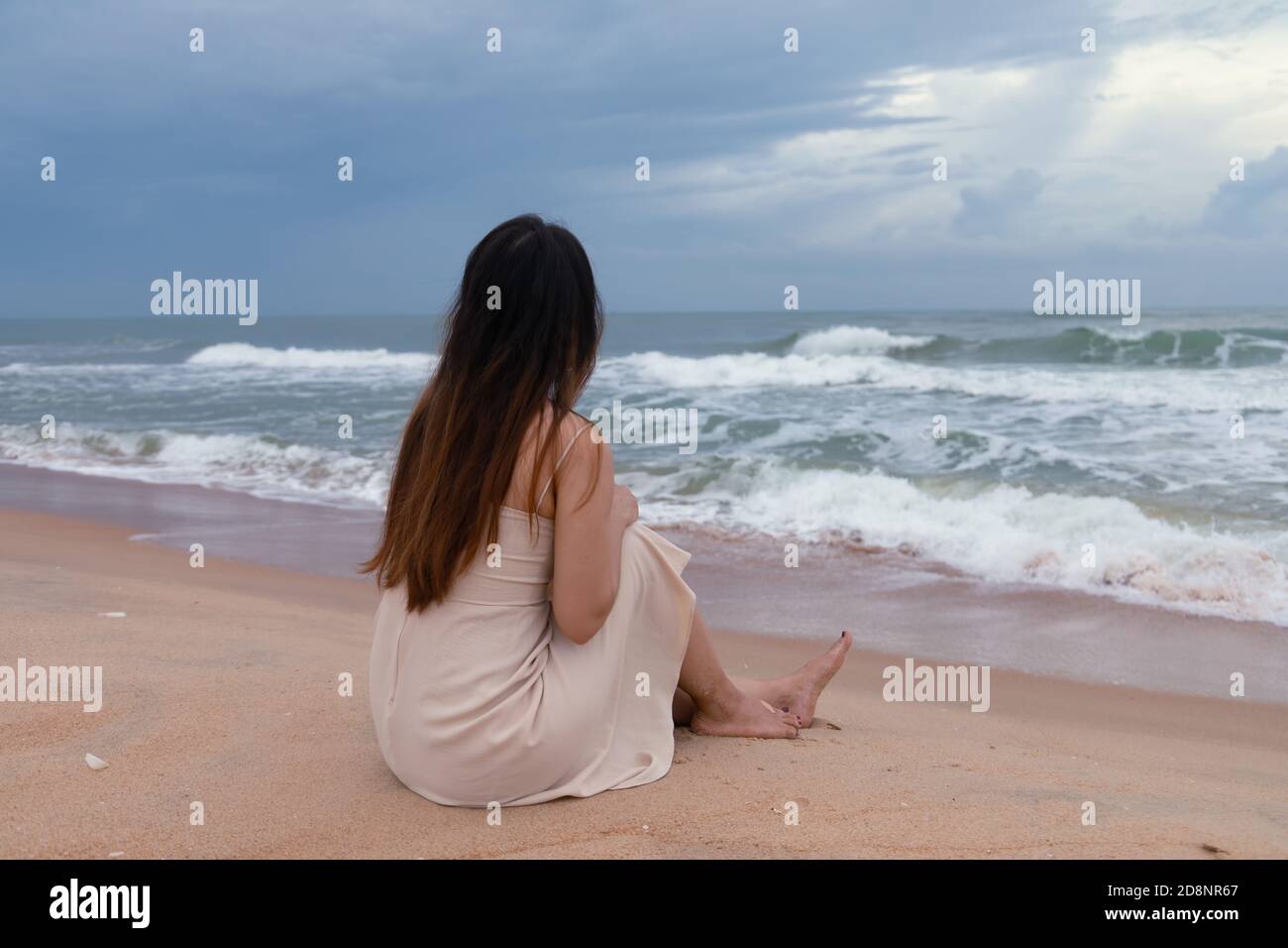 Beautiful Asian woman sitting on the sand near the beach and enjoying ...