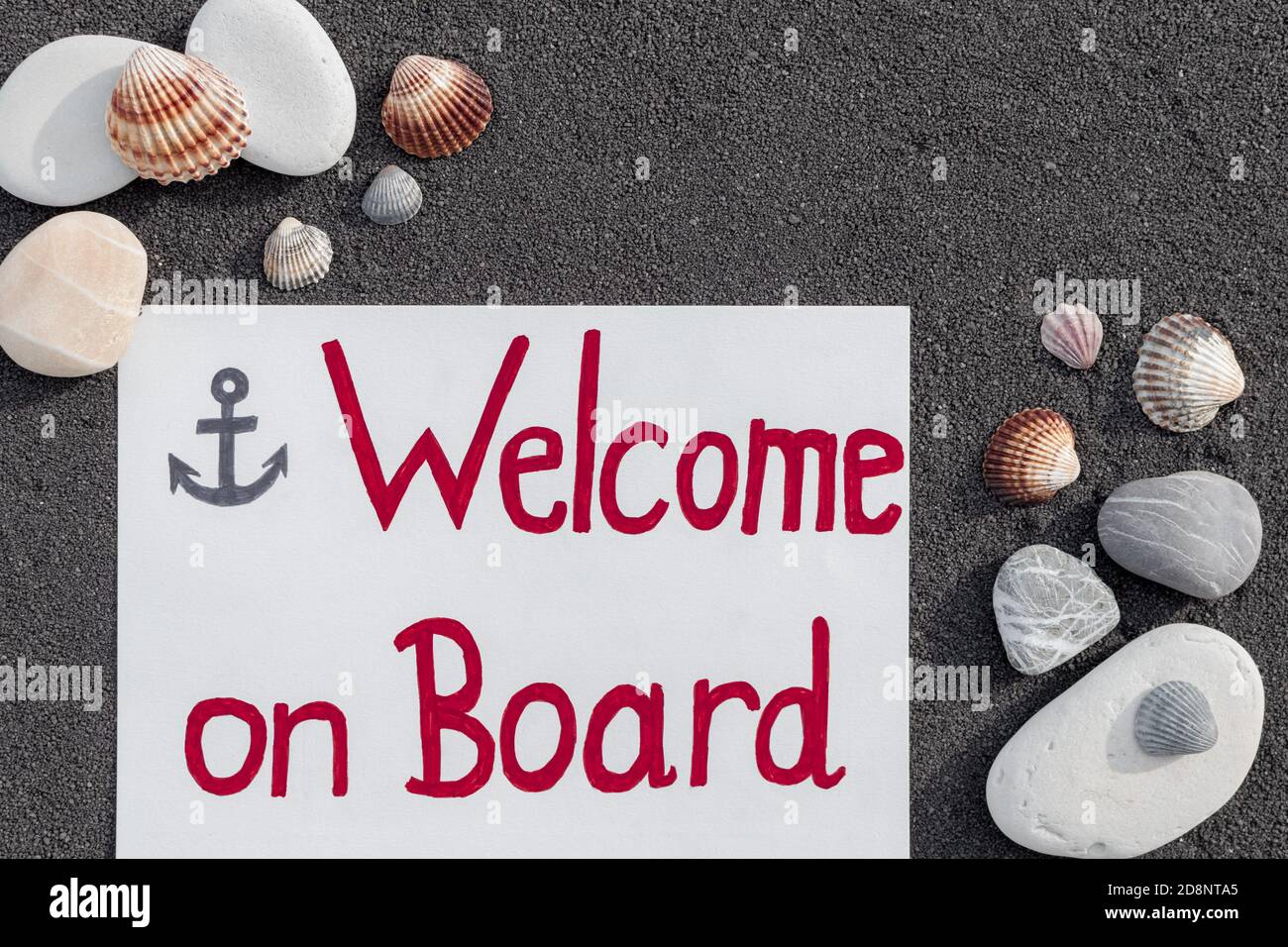 Welcome message on board on black sand background with pebbles and ...