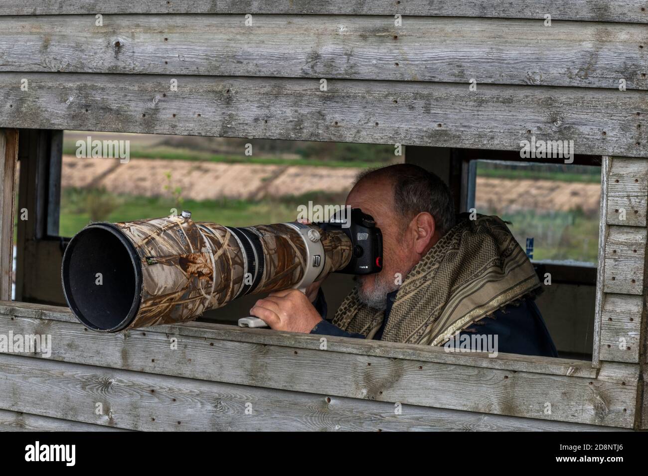 a birdwatcher or twitcher using a large lens on a camera to photograph ...
