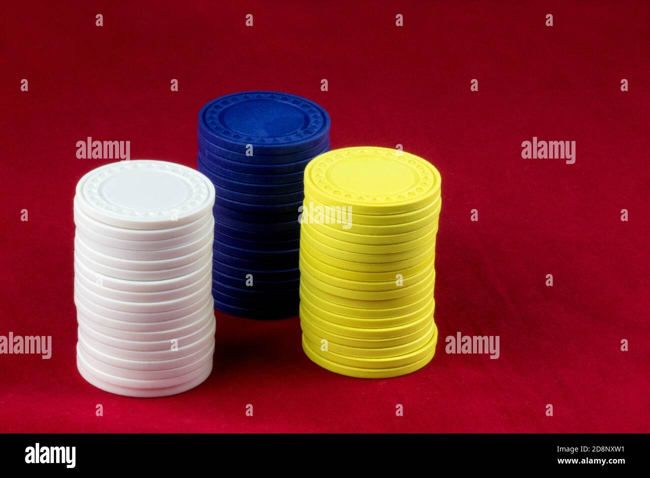 Coloured gaming chips stacked on a red table top Stock Photo - Alamy